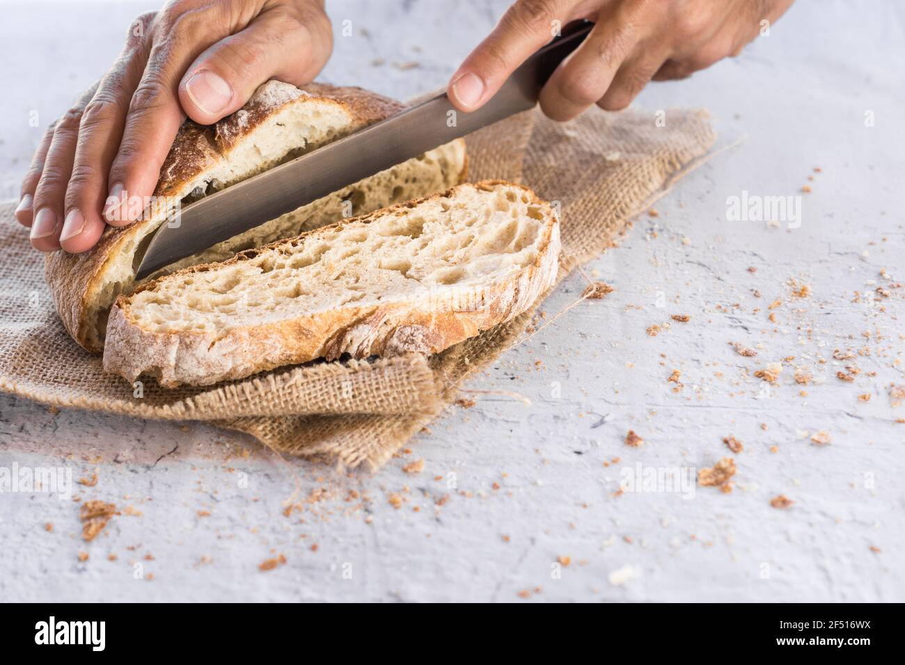 horizontal image of man's hands breaking organic bread in the ...