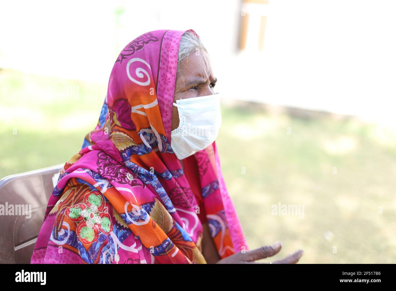 Closeup shot of an Indian woman with a traditional dress and white mask ...