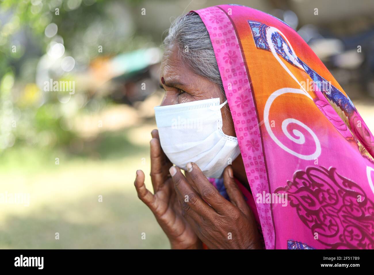 Closeup shot of an Indian woman with a traditional dress and white mask ...