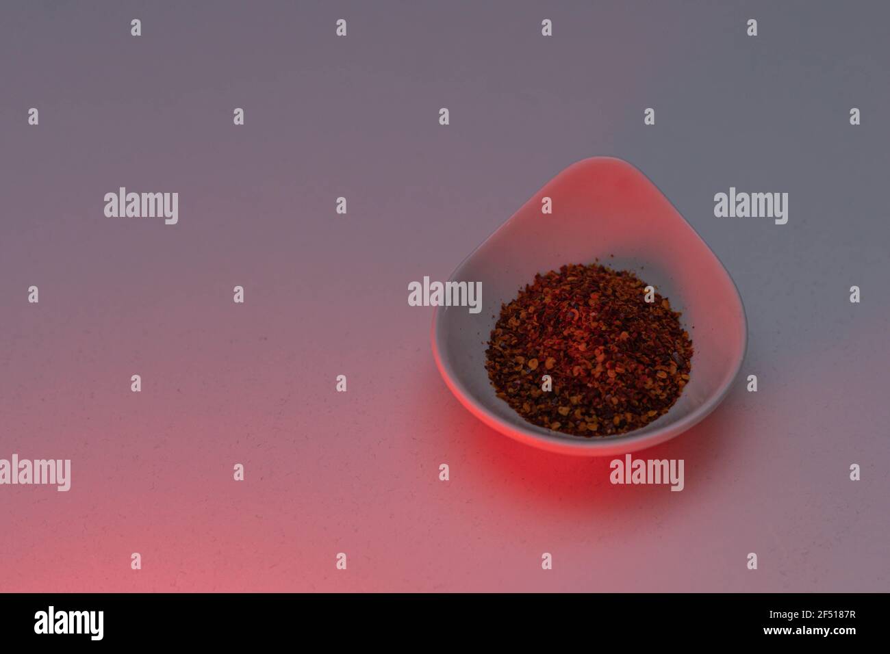 cayenne pepper flakes in a ceramic container with spicy food concept ...