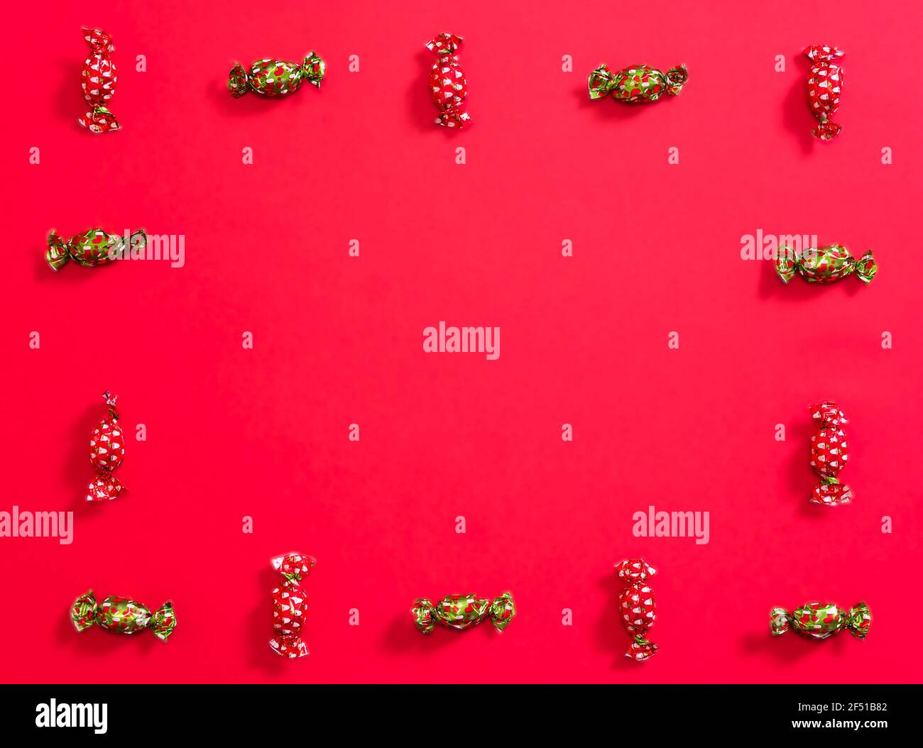 Christmas chocolates placed forming a frame on a red background ...
