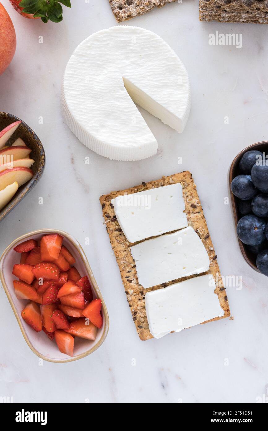 Overhead view of an almost whole fresh cheese with a healthy cracker ...