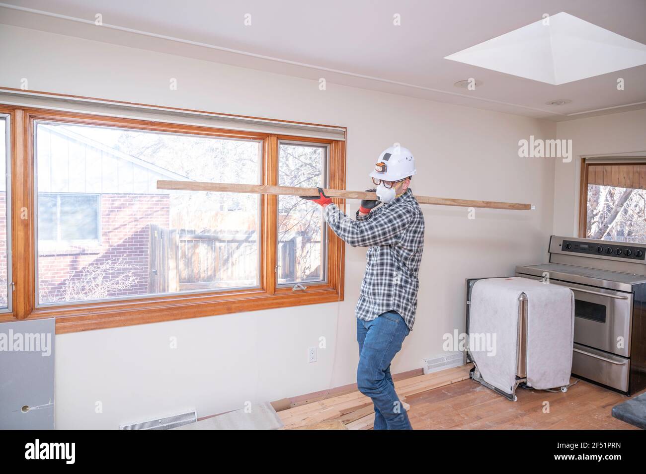 Contractor carrying a framing stud inside of a dining room during a ...