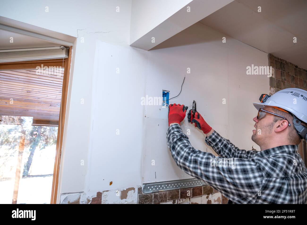 Electrician installing new wiring in wall of home during remodel ...