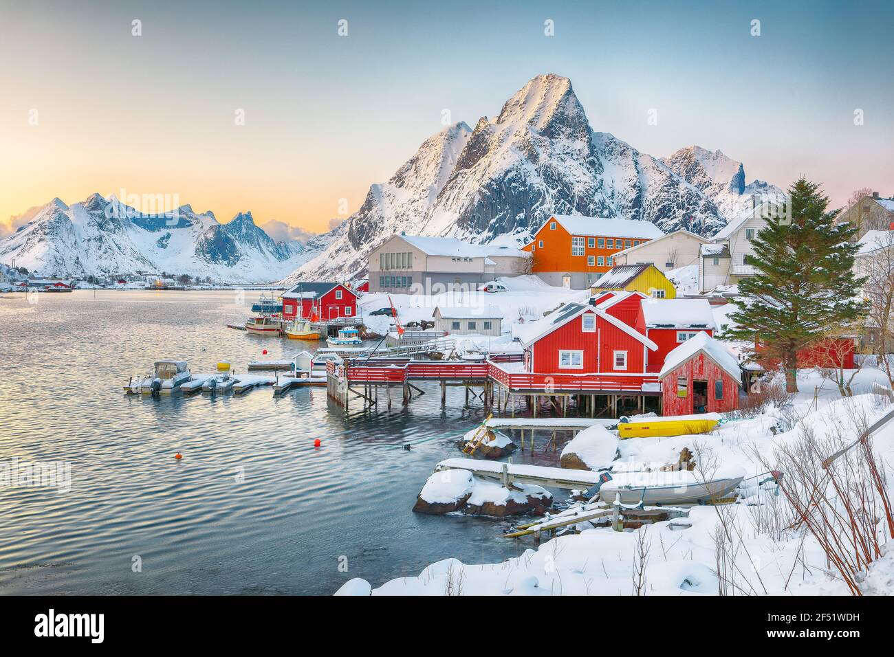 Astonishing evening cityscape of Reine town. Red rorbuers on the shore ...
