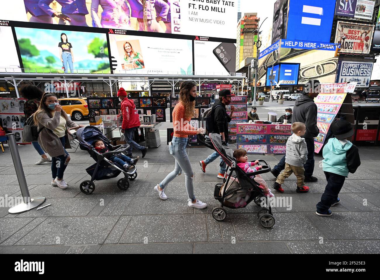 Two women and their families walk through Times Square on a warm and ...
