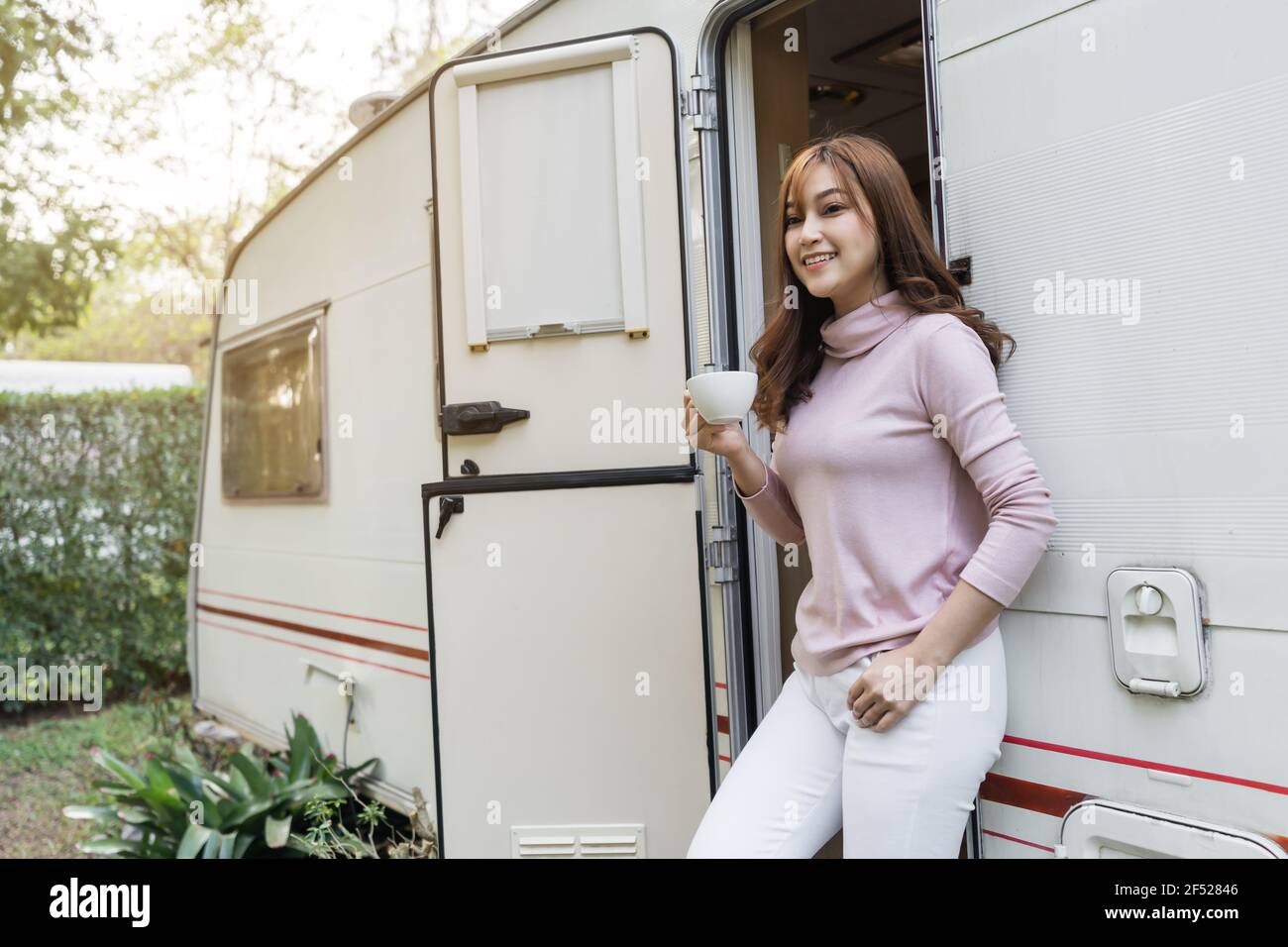 happy young woman drinking coffee at door of a camper RV van motorhome ...