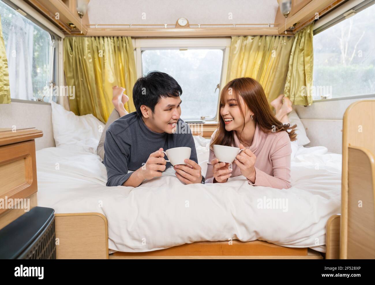 happy young couple drinking coffee in bed of a camper RV van motorhome ...