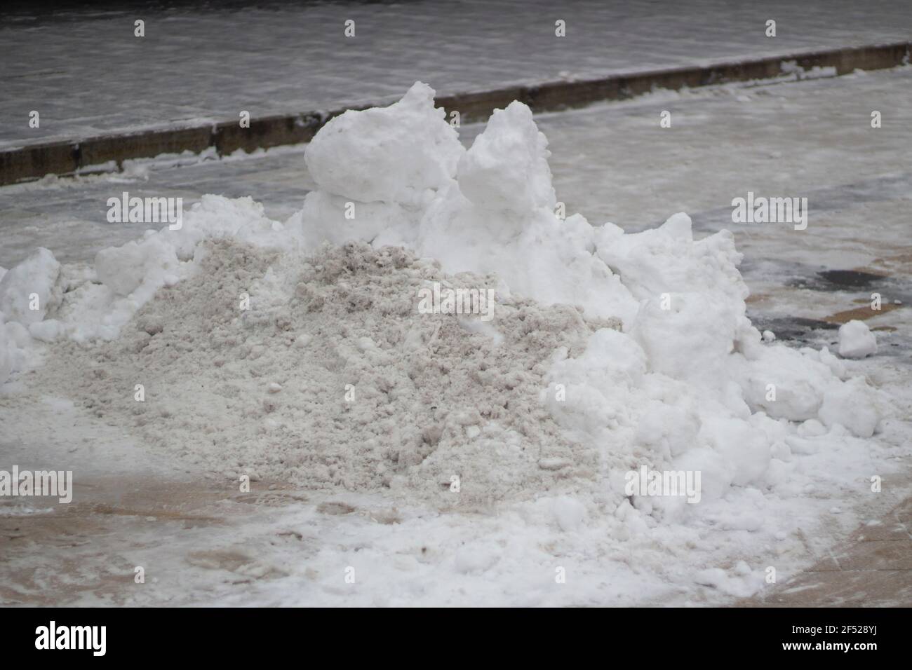A mountain of snow on the street. Rainfall in the city in spring ...