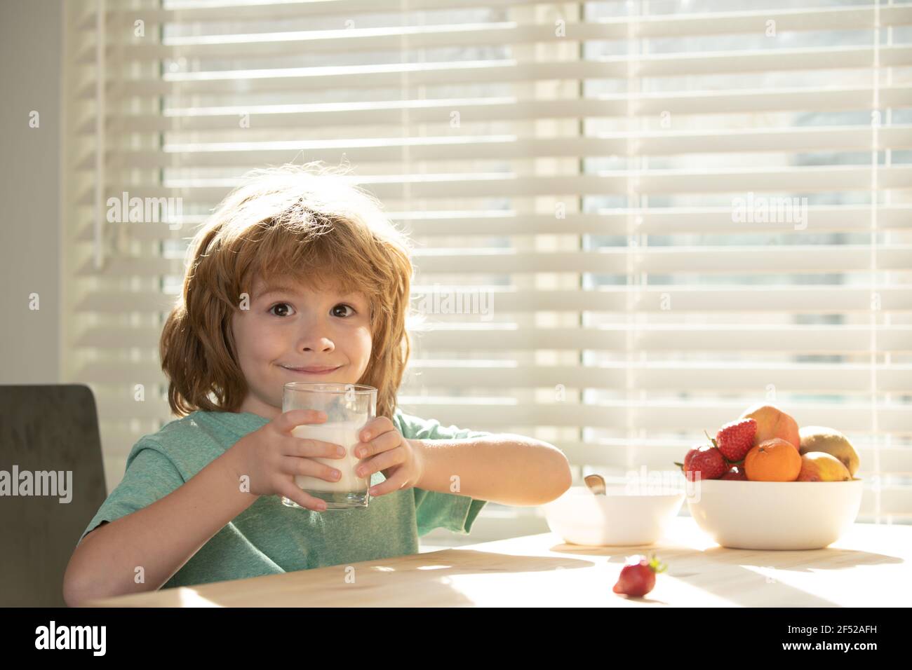 Food and drink for kids. Funny happy cute kid with glass drink milk sit ...