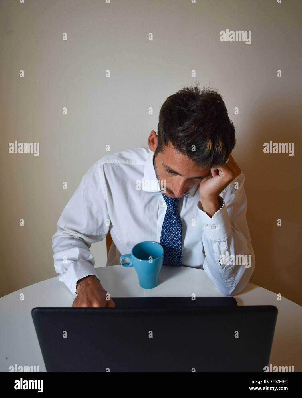 Tired businessman leaning his head on his hand while working on his ...