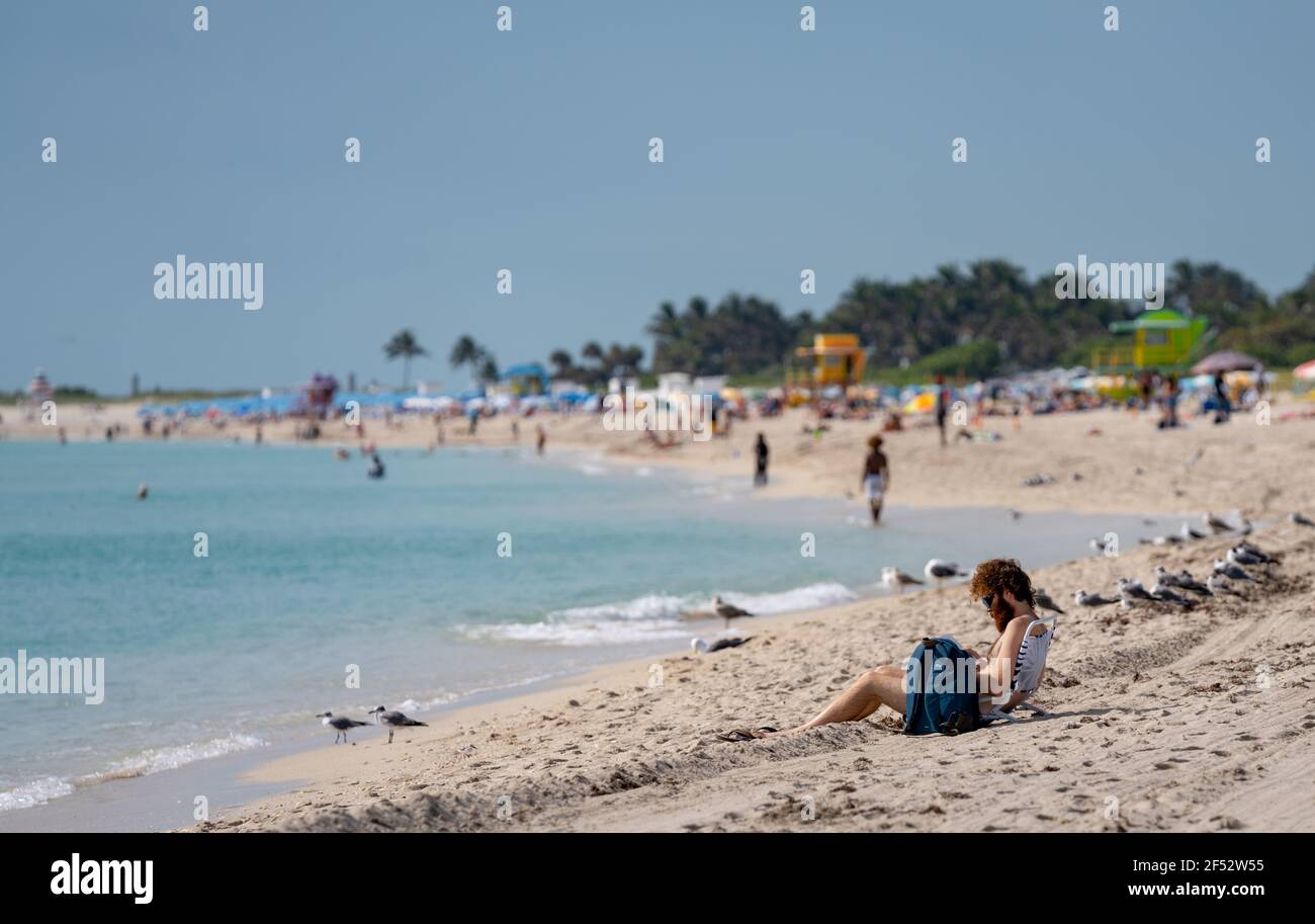 Man laying on the sand during Miami Beach spring break Stock Photo - Alamy