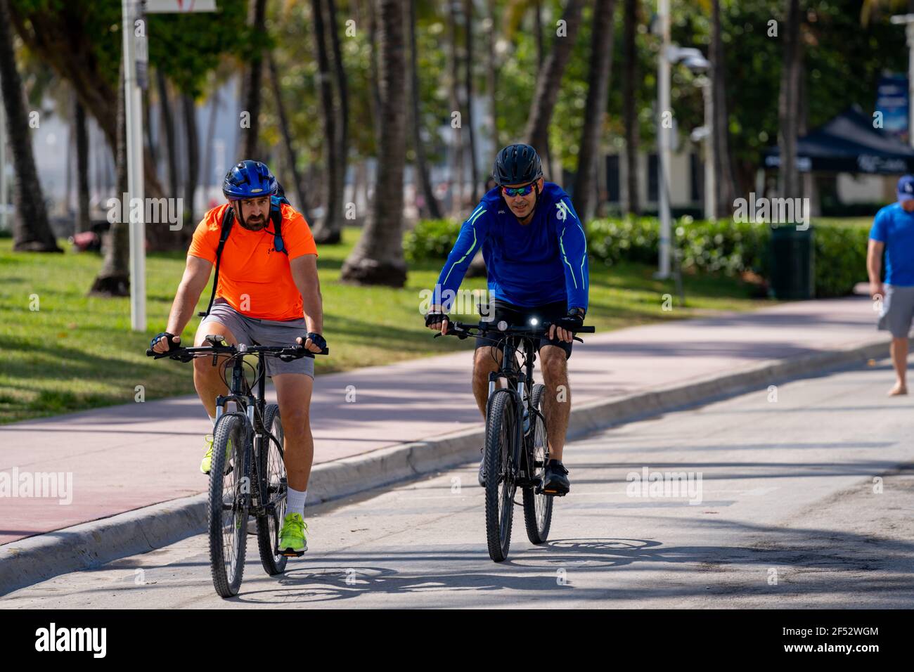 Two men riding bikes in Miami Beach on Ocean Drive Stock Photo - Alamy