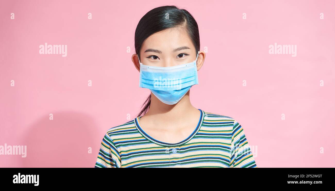 A close-up portrait of a pretty female wearing a surgical mask isolated ...