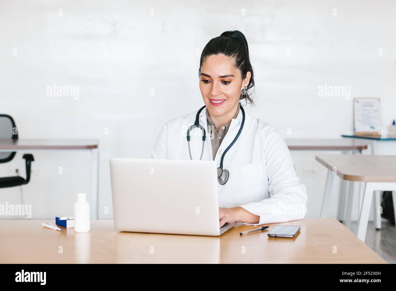 latin doctor woman consulting online and working with computer at ...
