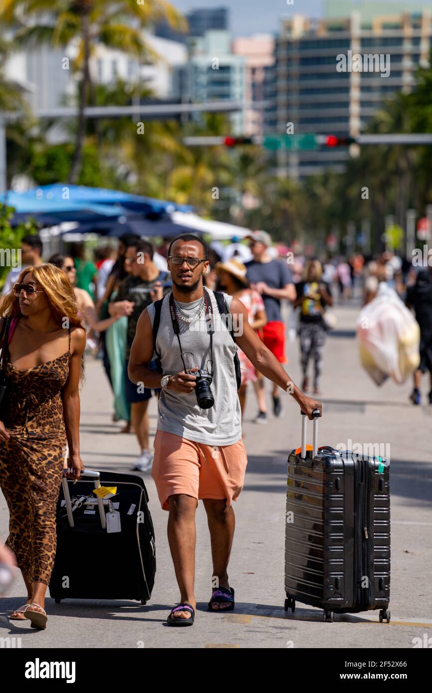 Miami Beach spring break scene man walking with luggage and camera ...