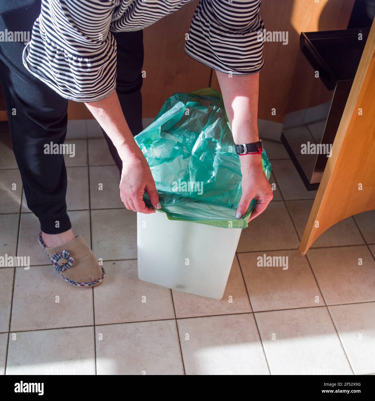 A woman replaces plastic bag on a rubbish bin, indoor cropped image ...