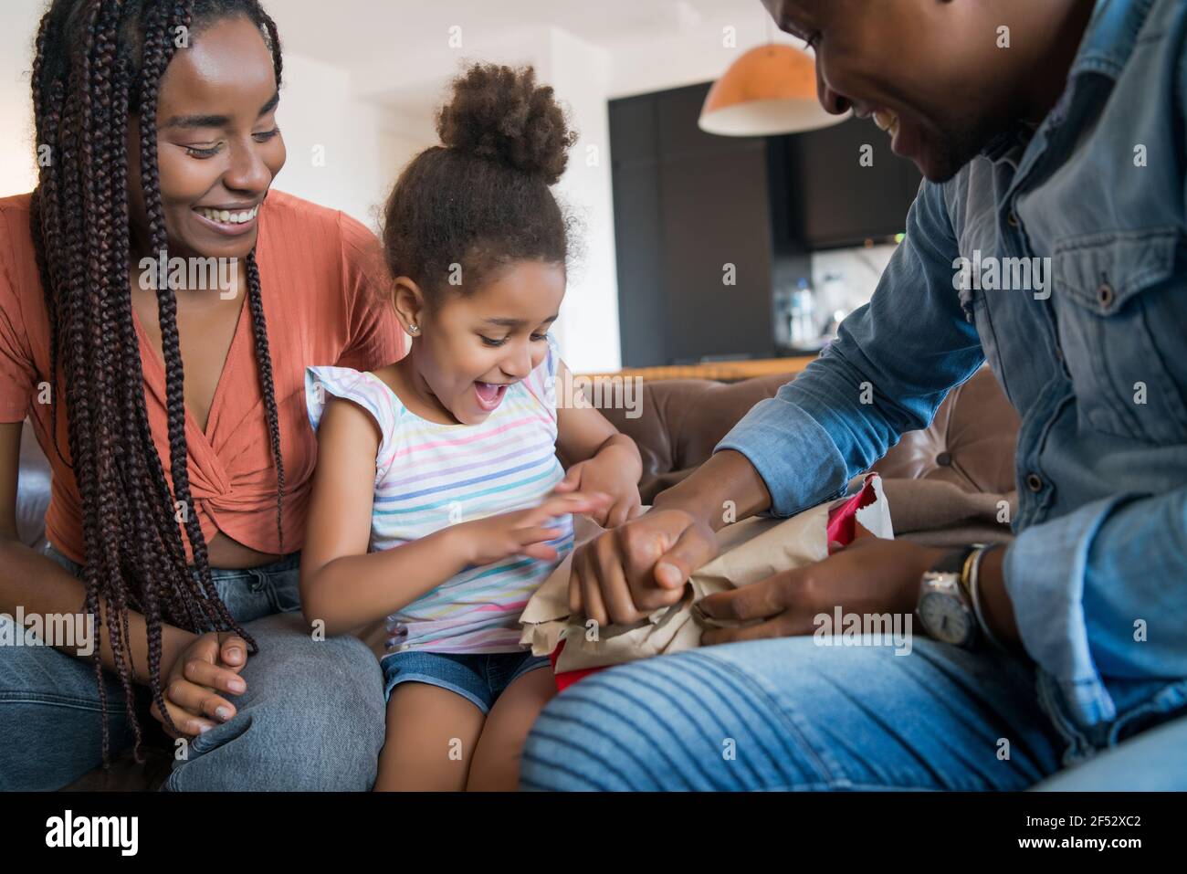 Little girl receiving gift from her parents Stock Photo - Alamy