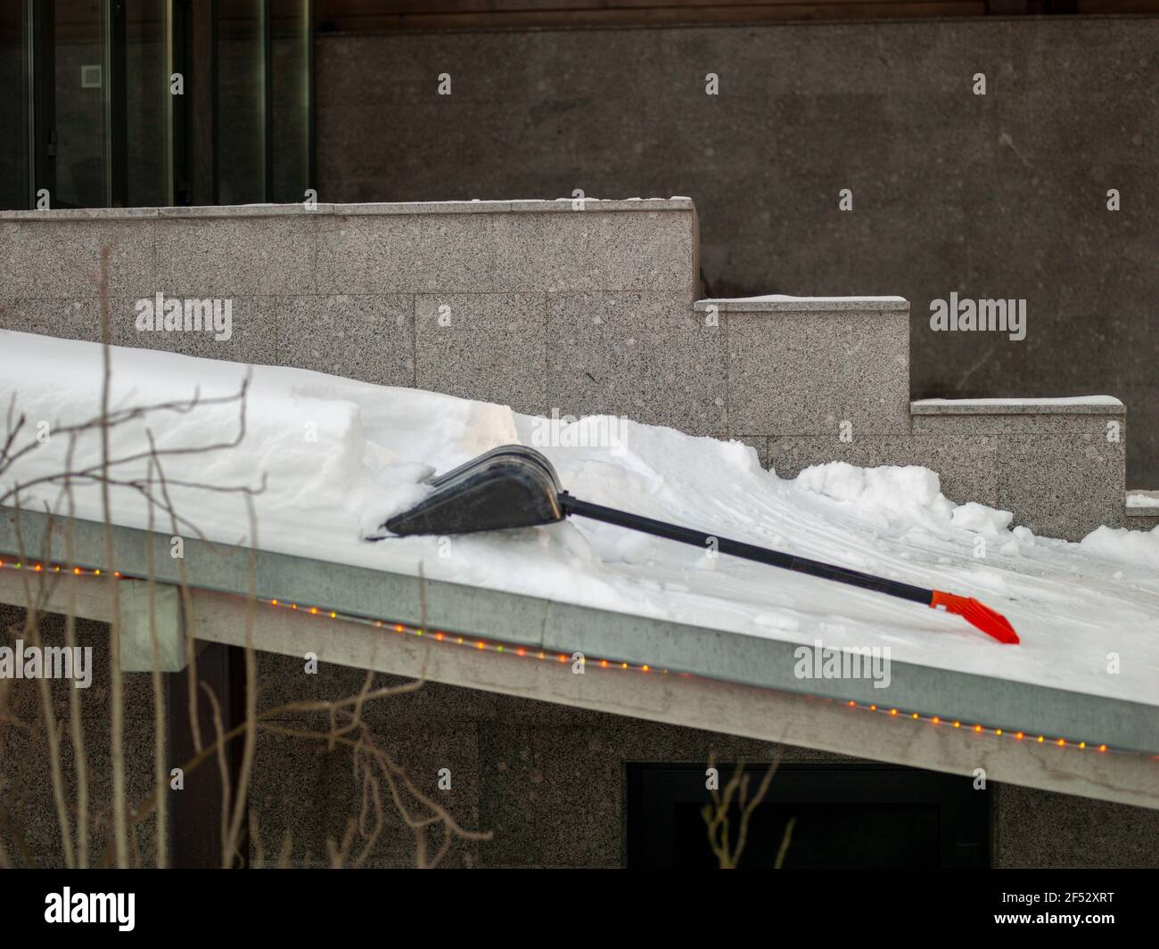 Removing snow from a ledge outside a house, abandoned shovel out of ...