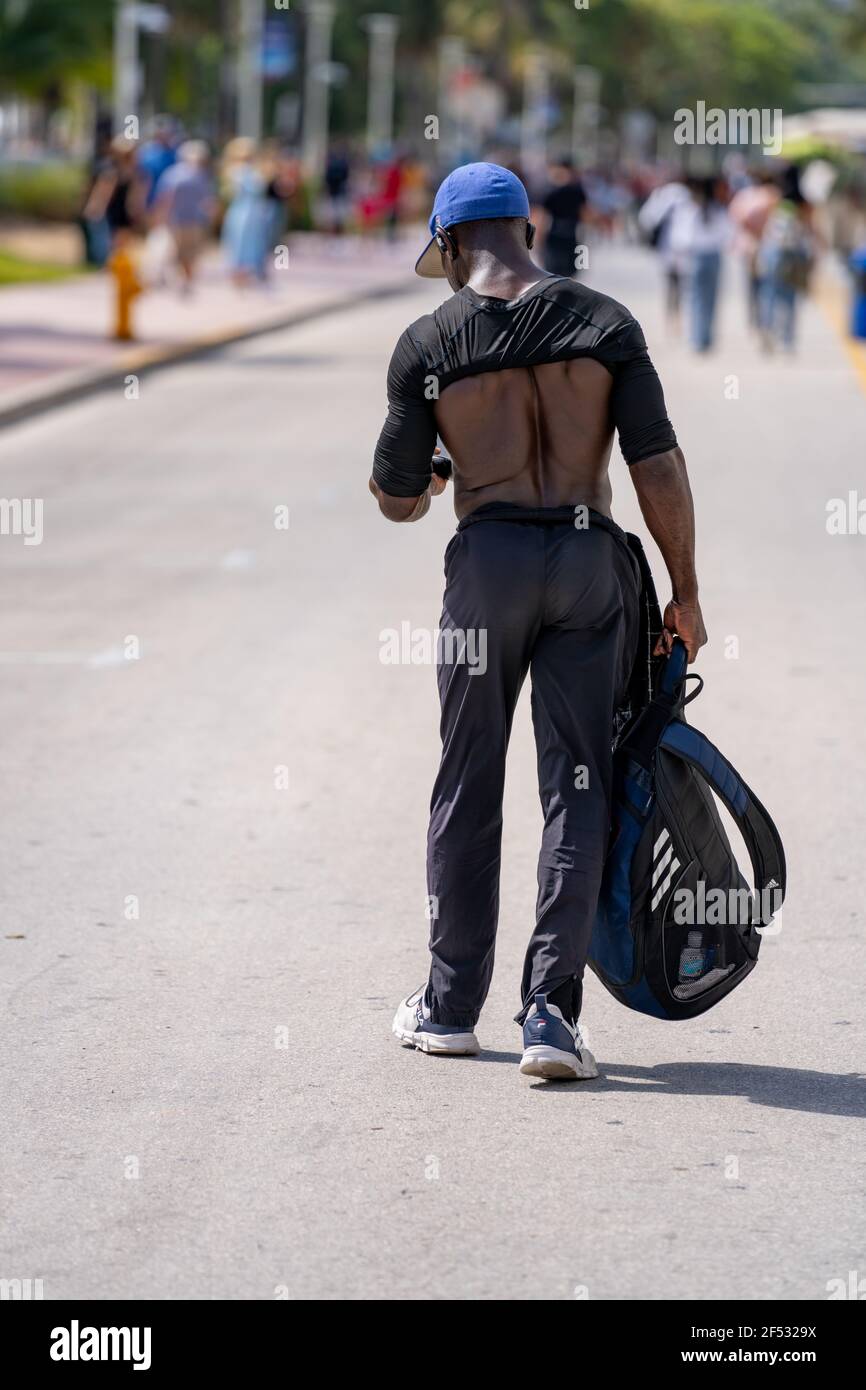 Male fitness model facing away from camera with shirt rolled to reveal ...