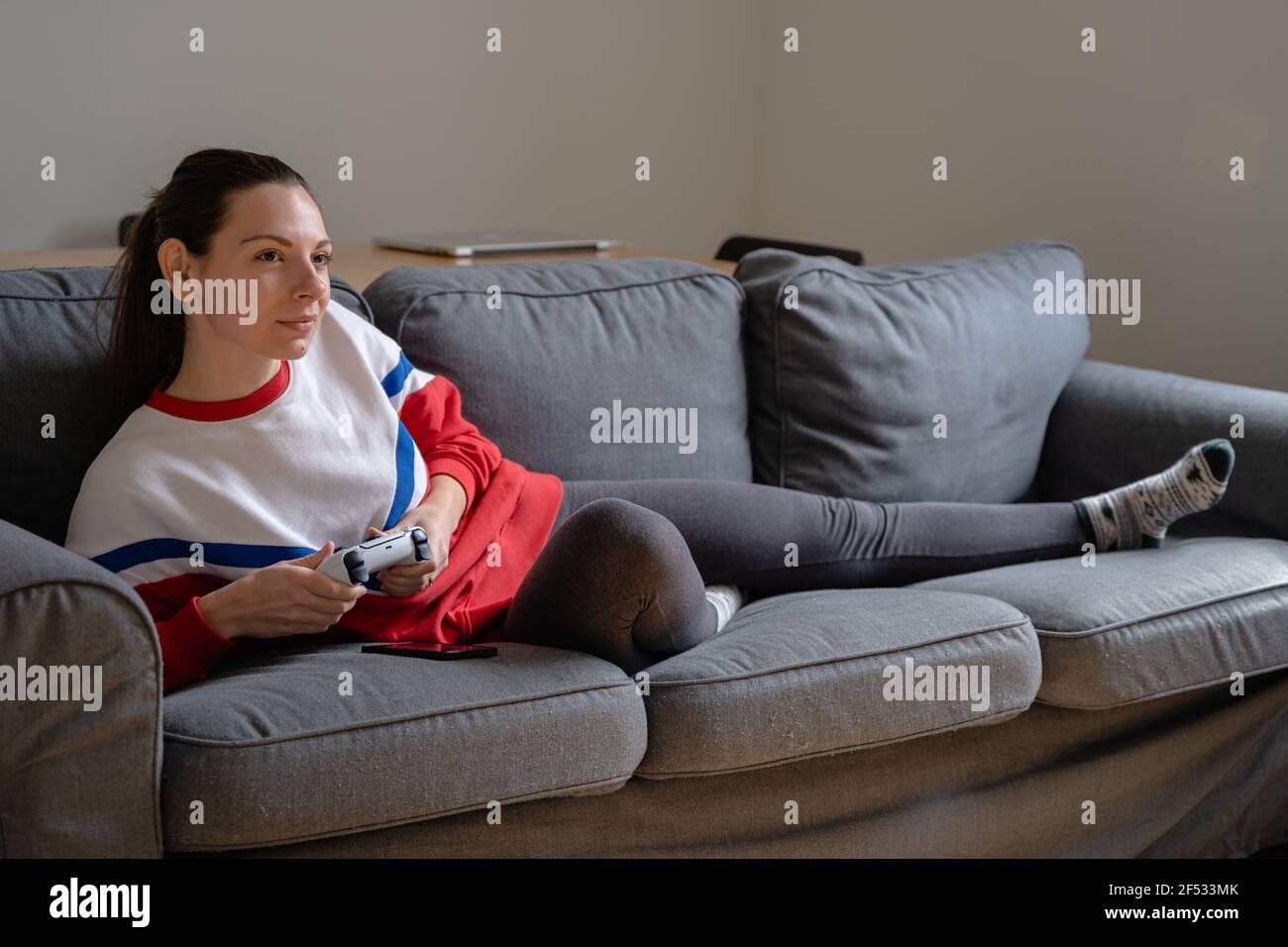 woman at home playing video games with wireless gamepad. Console gaming ...