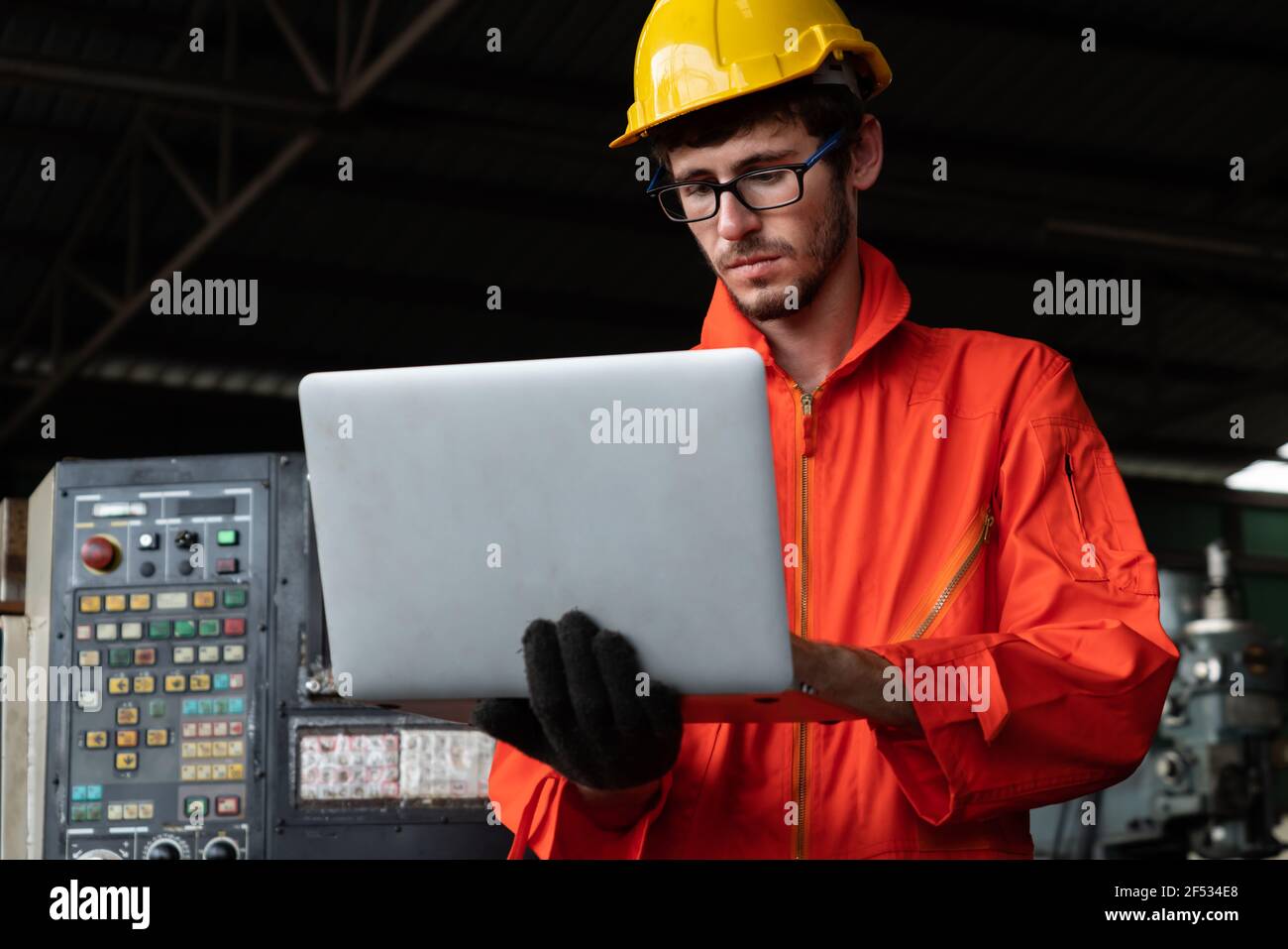Skillful factory worker working with laptop computer to do procedure ...