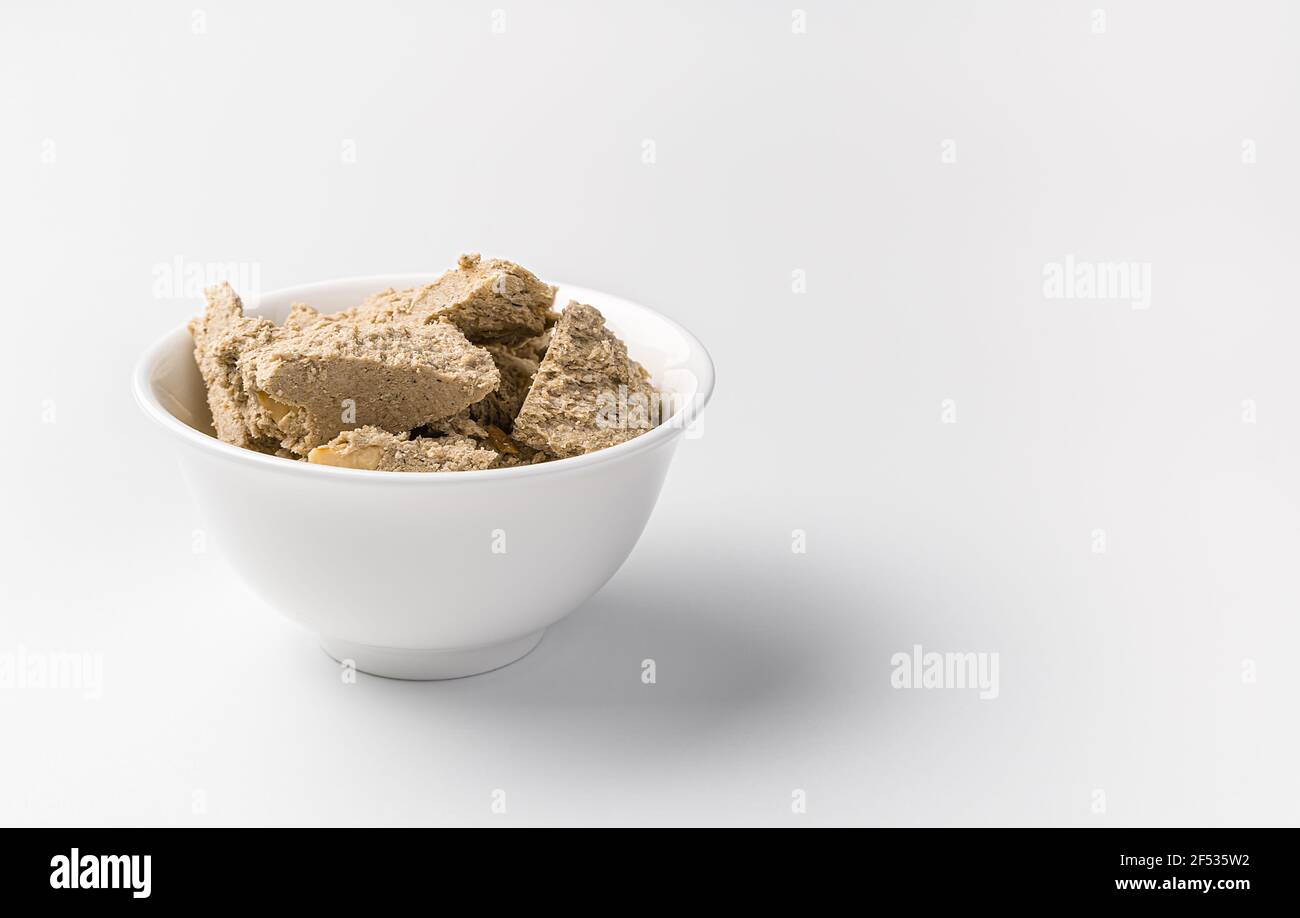Small pieces of halva in a cup on a light background. Side view with ...
