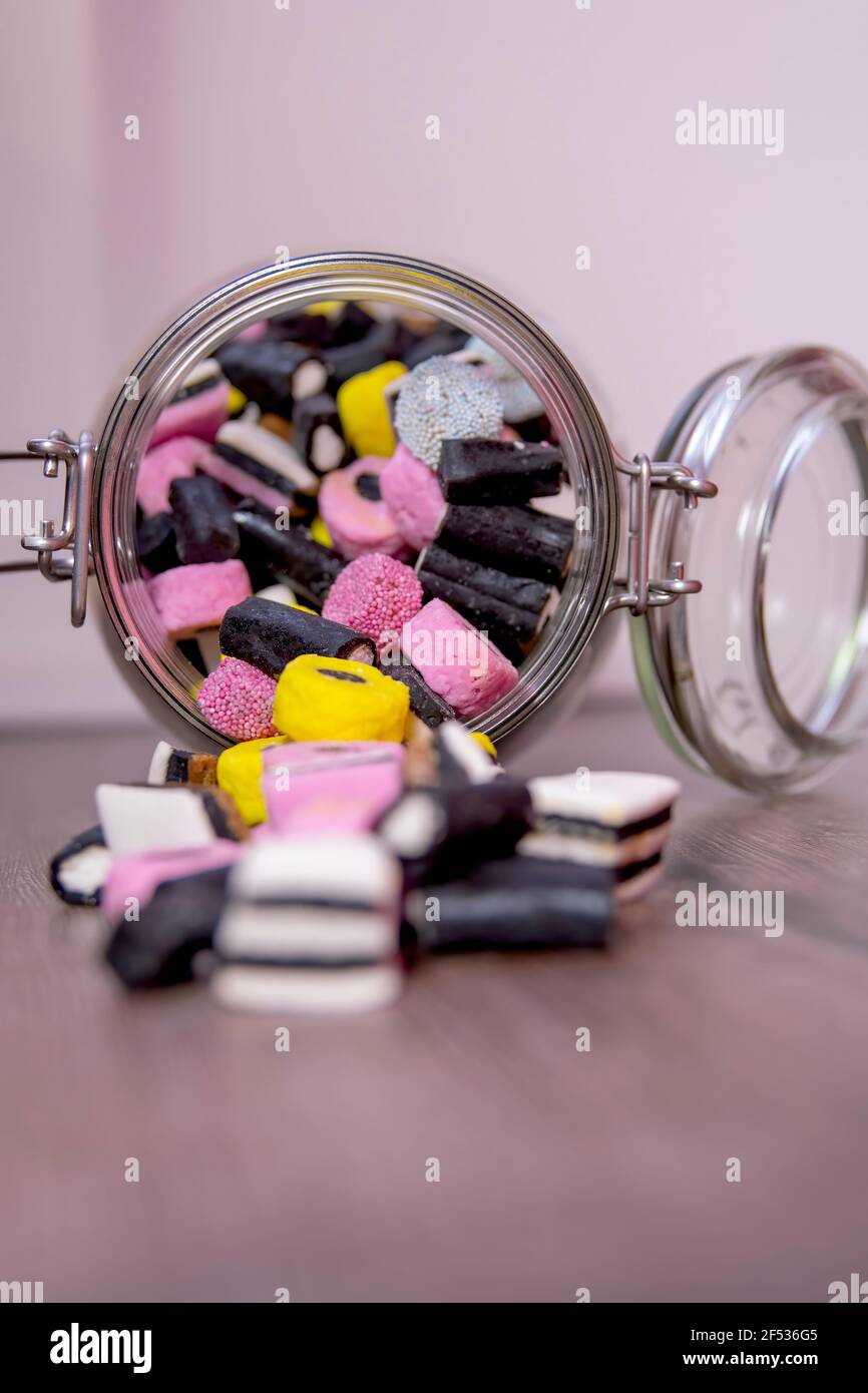 Candy glass jar opened on a table and Licorice candy sweet fell out if ...