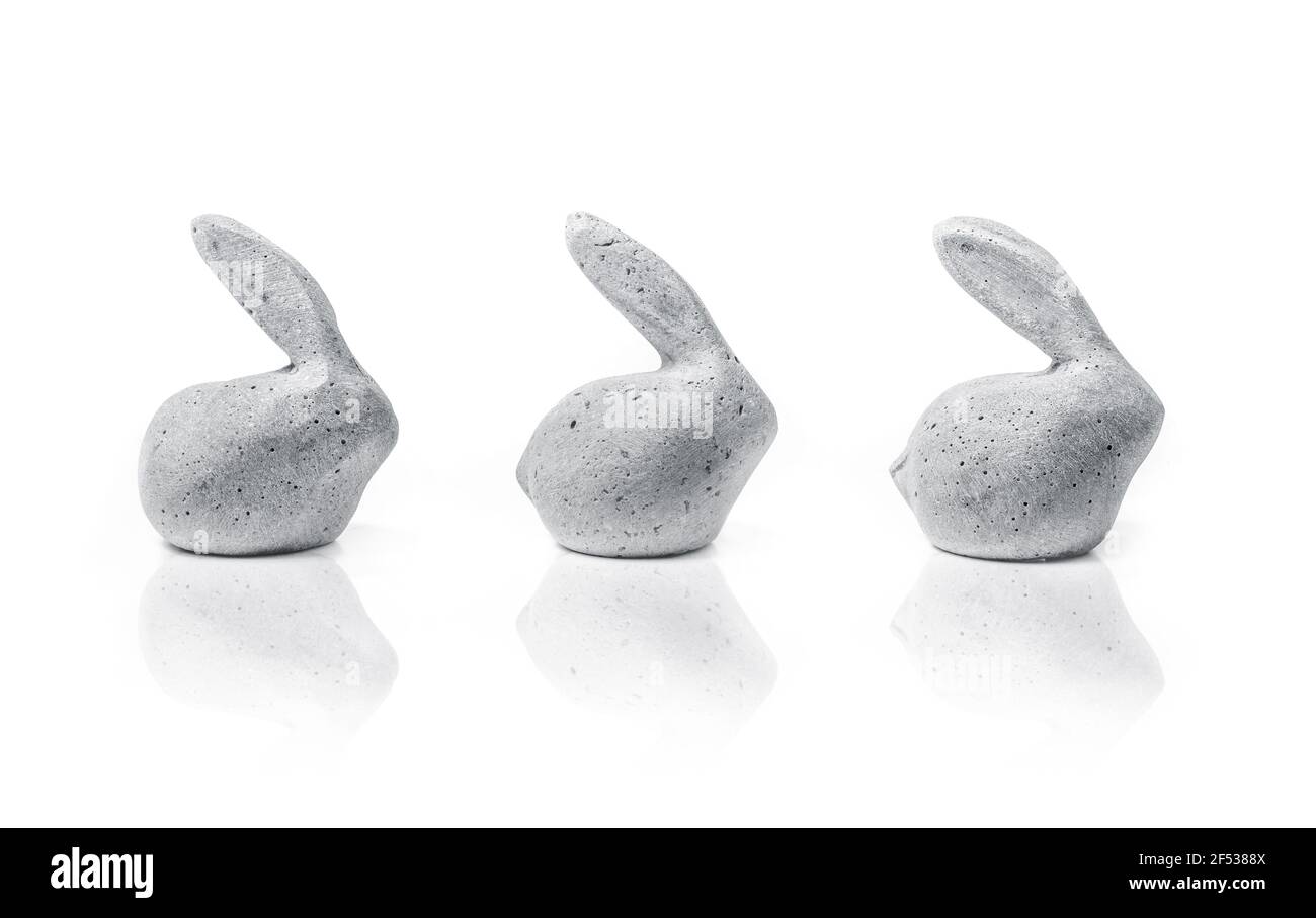 Three small stone rabbits. Side profile of tiny adorable simple Easter ...