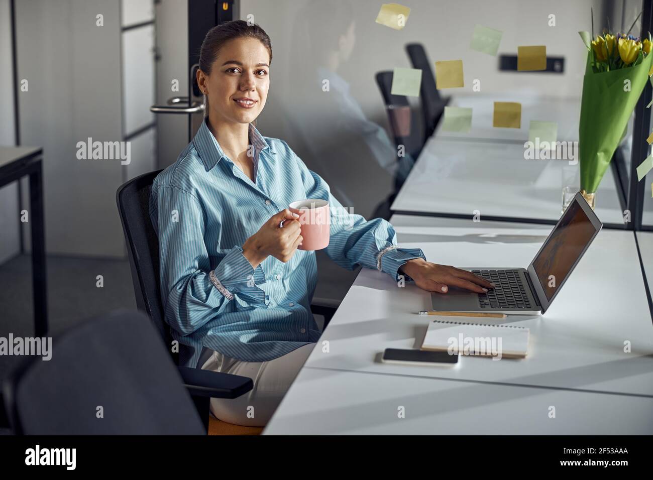 Young lady seated at the desk during the tea break Stock Photo - Alamy