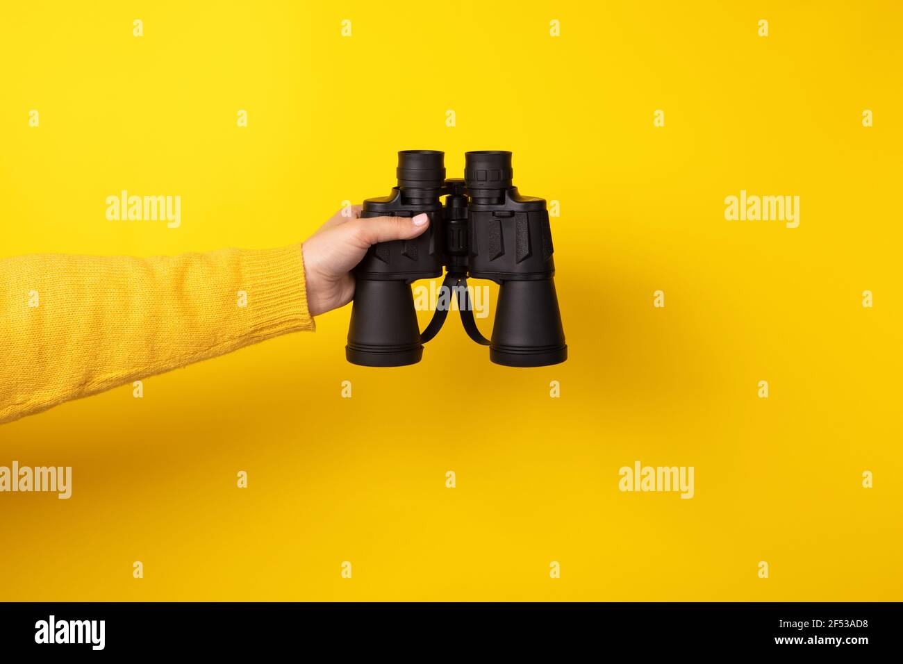 binoculars in hand over yellow background, search concept Stock Photo ...