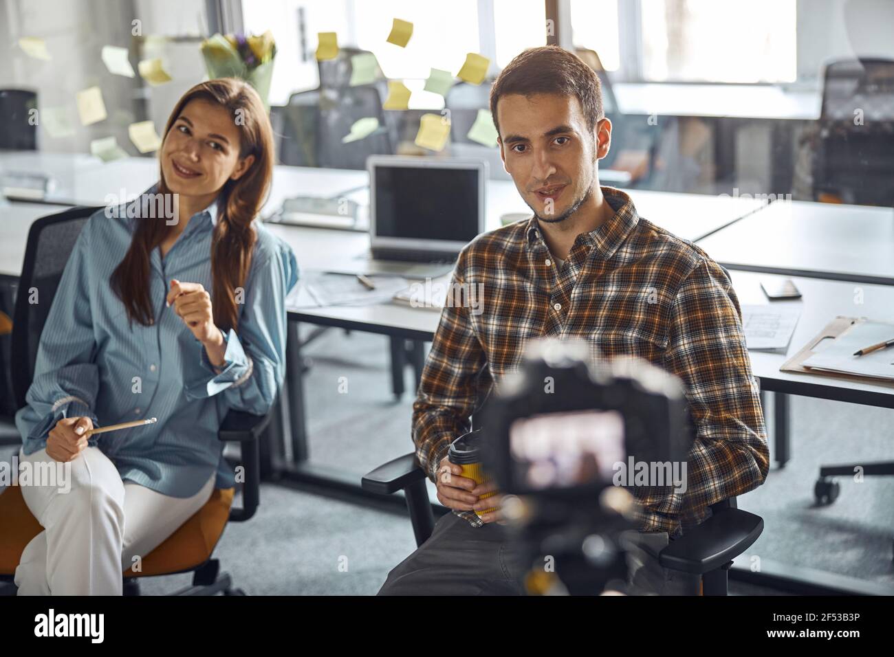 Two young office workers being filmed with the camera Stock Photo - Alamy