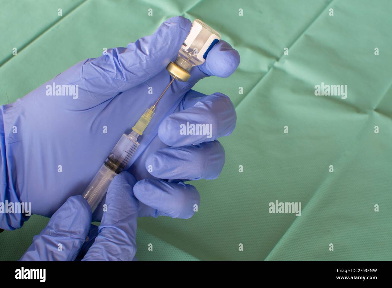 Health care worker hand in purple glove preparing a syringe in front of ...