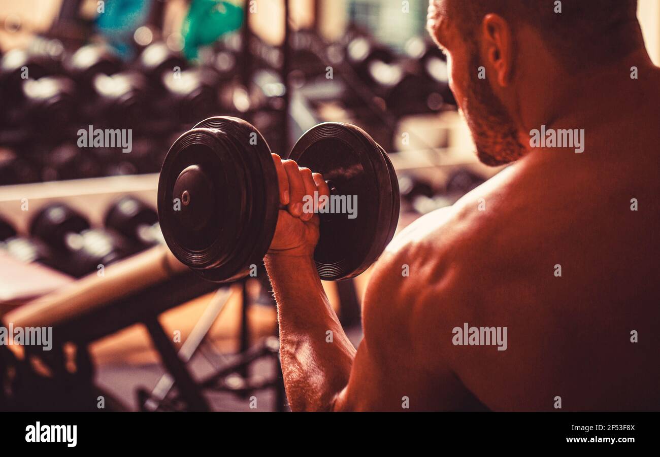 Man lifting dumbbell in a gym making exercise for muscles. Bodybuilder ...