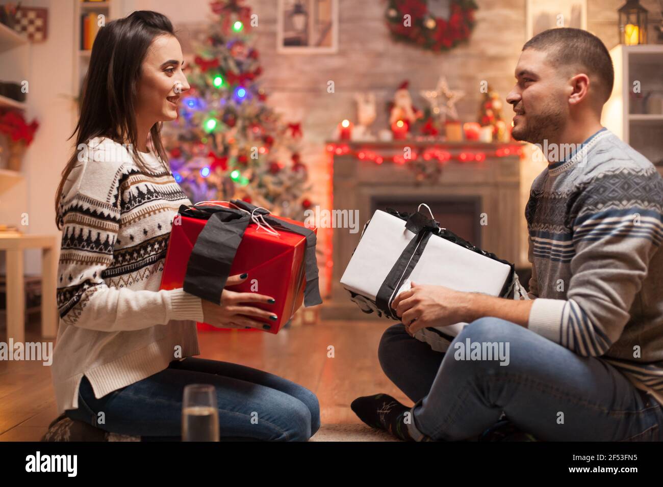 Happy girlfriend and boyfriend on christmas day giving each other gifts ...