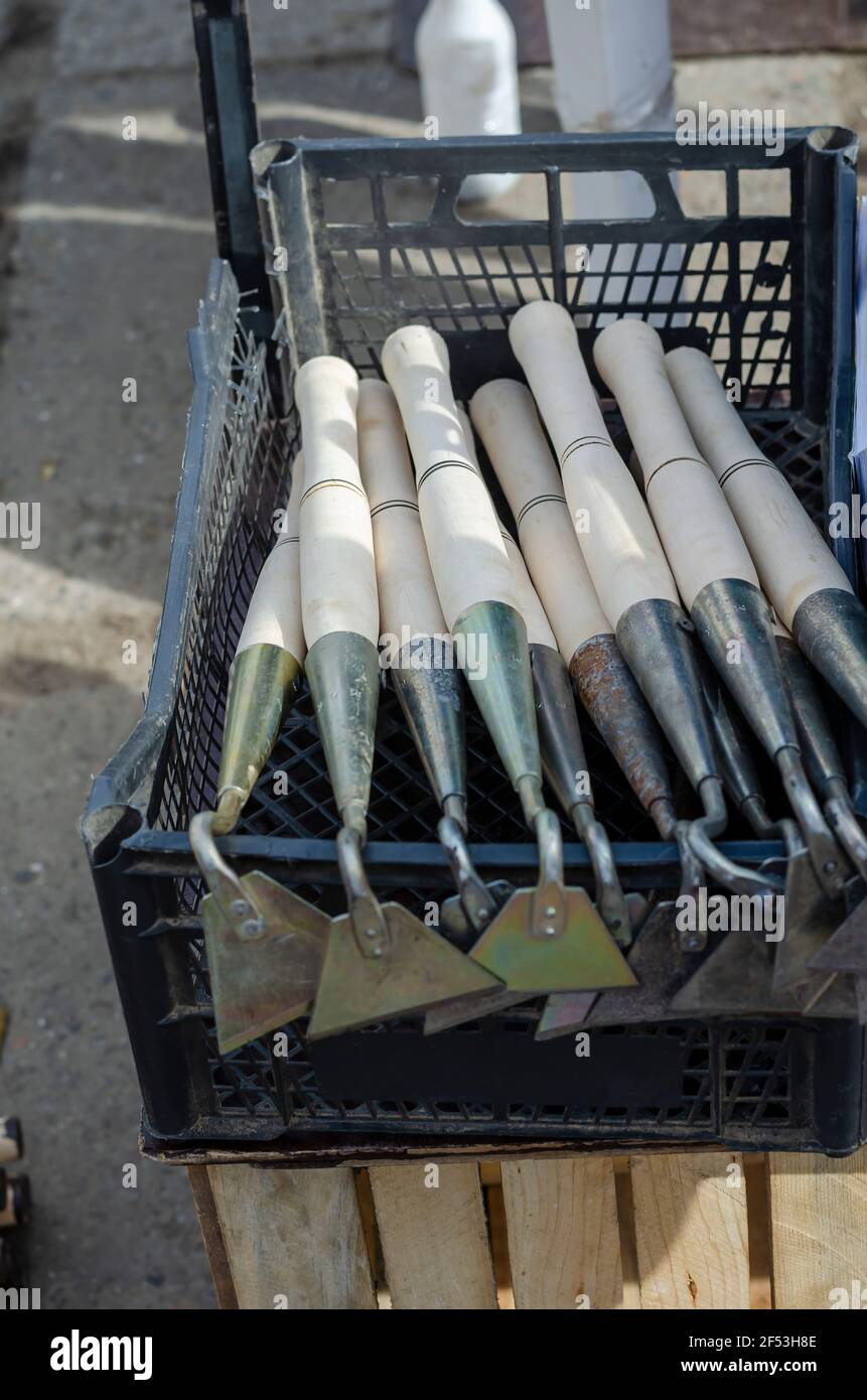A counter with new metal garden tools. Garden hoes with wooden handles ...
