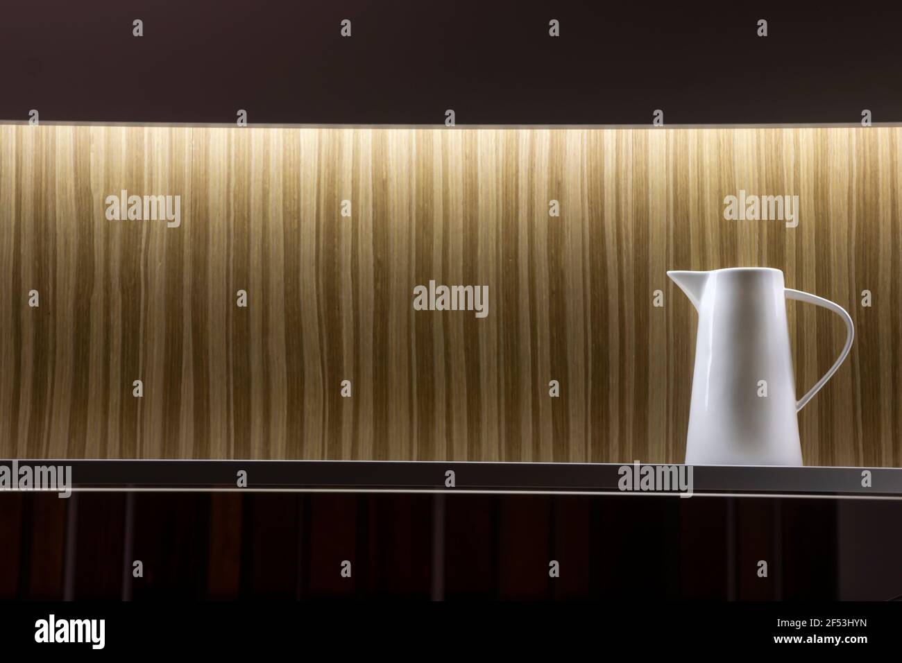 A modern white jug with simple classic lines sitting on a kitchen shelf ...