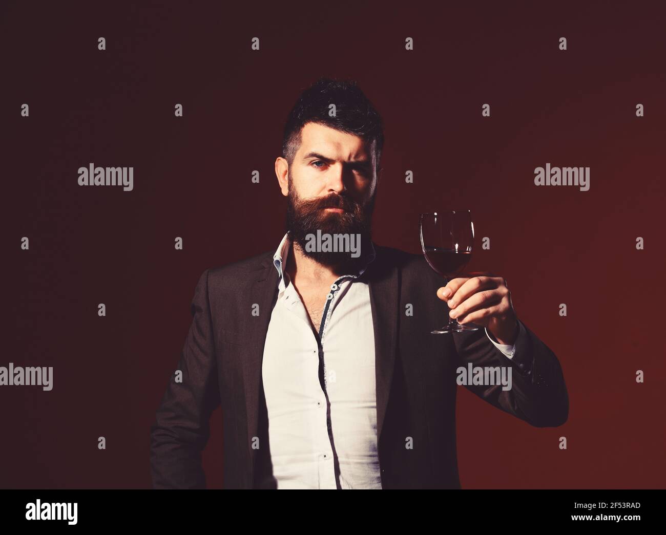Man in suit toasting with sparkling glass of red wine Stock Photo - Alamy