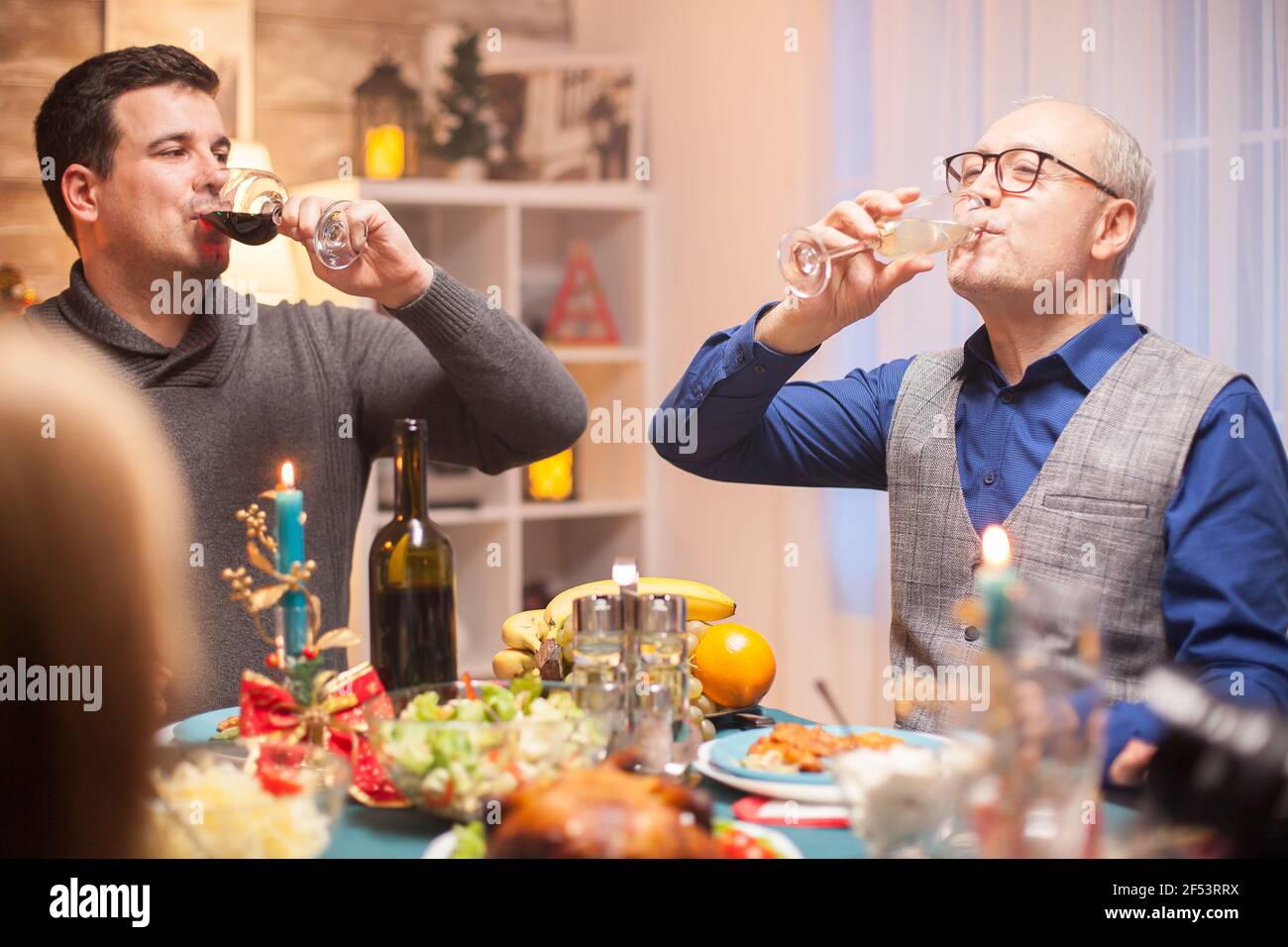 Happy senior man and his son drinking a glass of wine together at ...