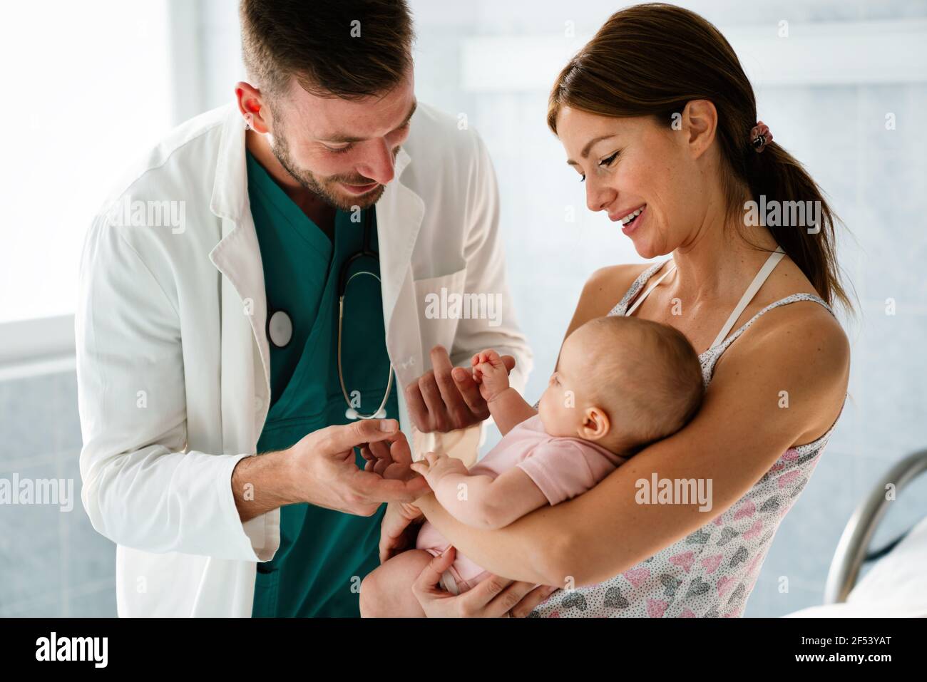 Pediatrician doctor medical examining little smiling baby, held by ...