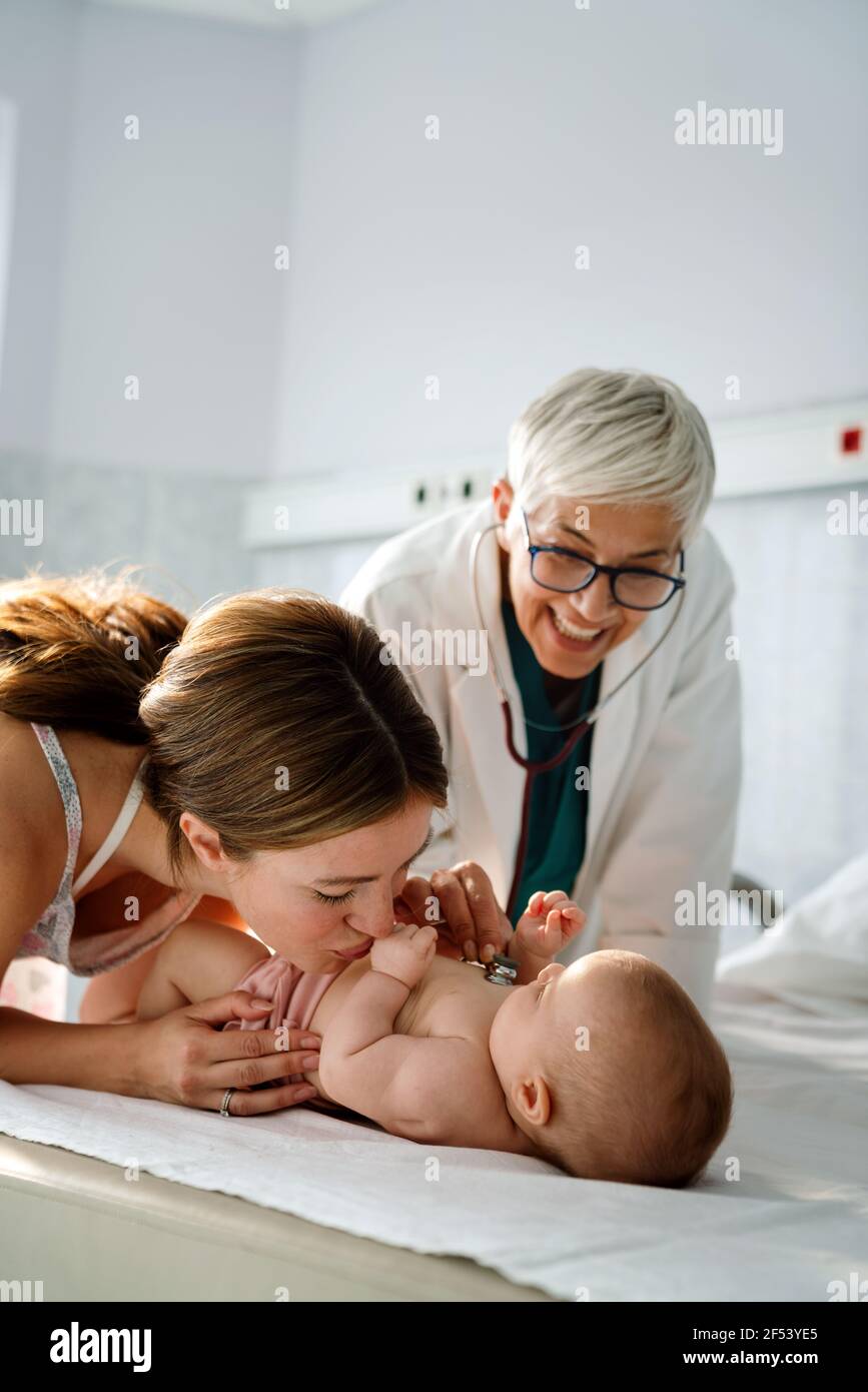 Pediatrician doctor medical examining little smiling baby, held by ...