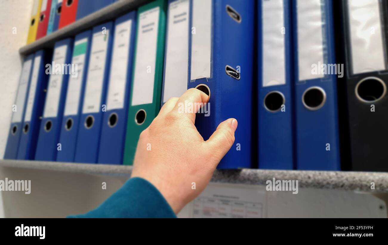 Man hand reaching for a blue office Paper folder in a row with ...