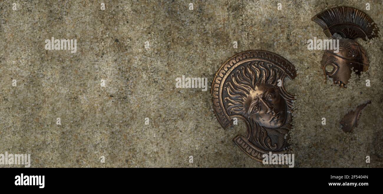 Toy of roman sun god shield and helmet buried in sand Stock Photo - Alamy