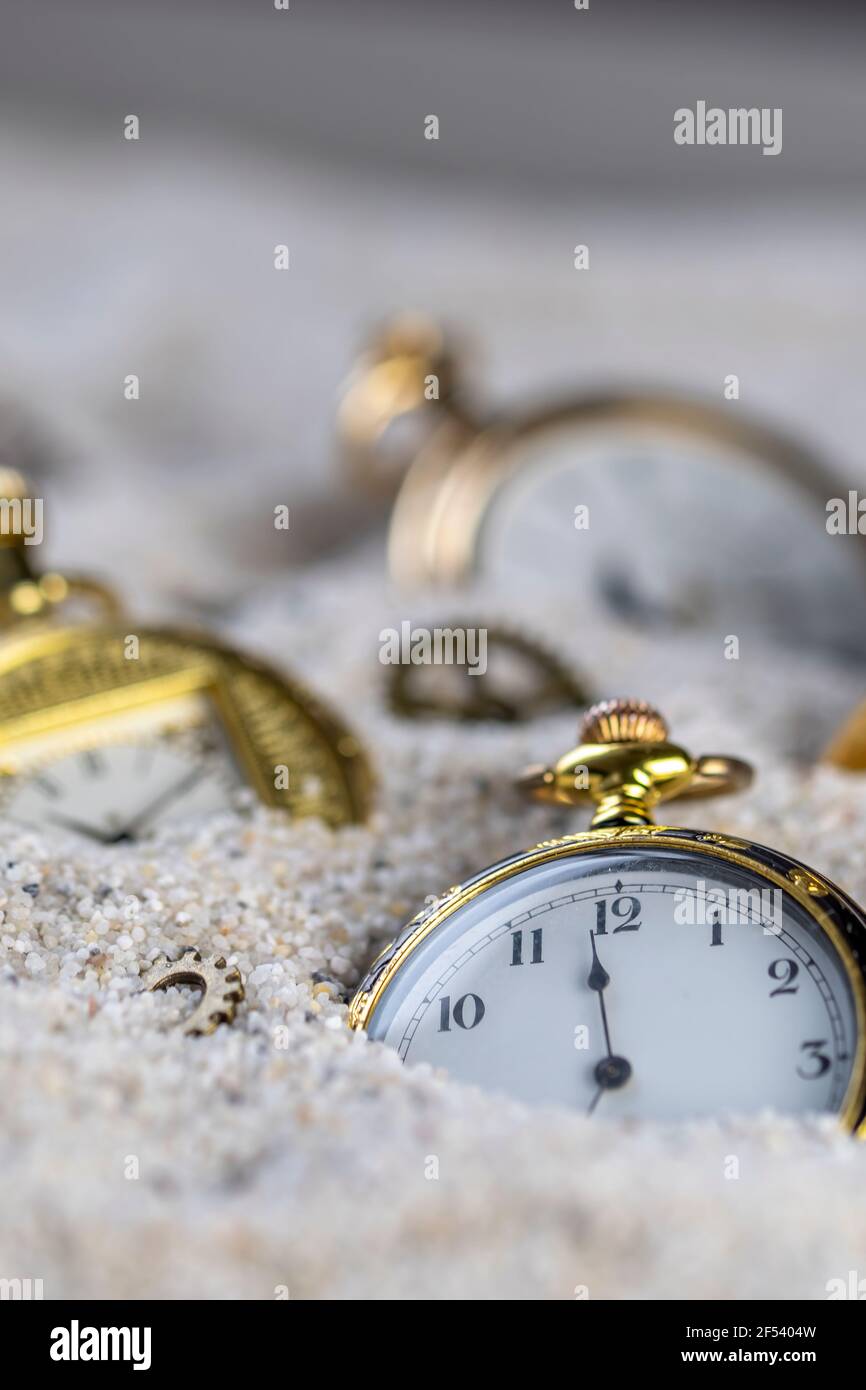 Macro photography of many or group of old gold pocket watches on sand ...