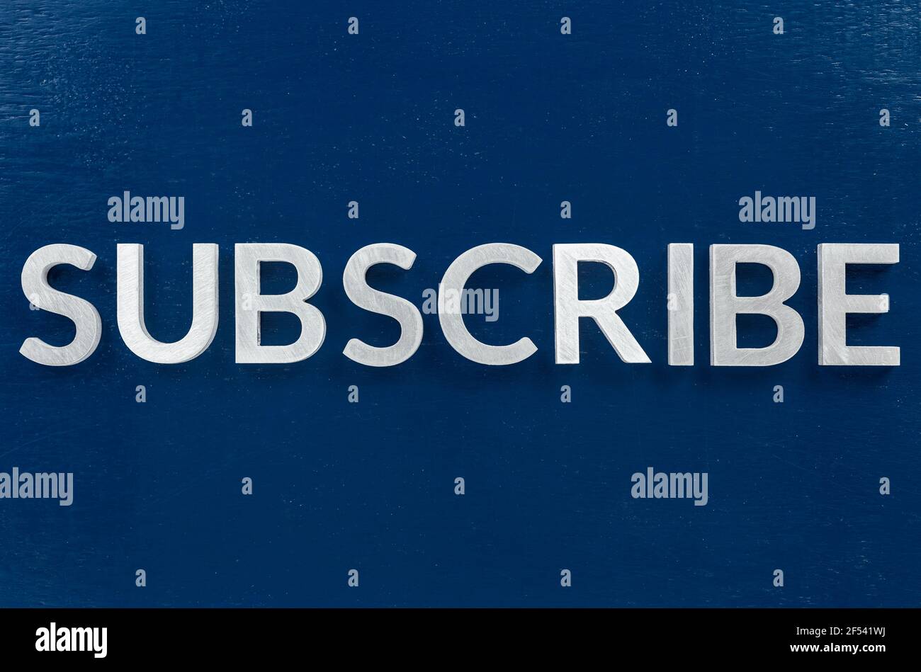 the word subscribe laid with aluminium letters on blue paint board ...