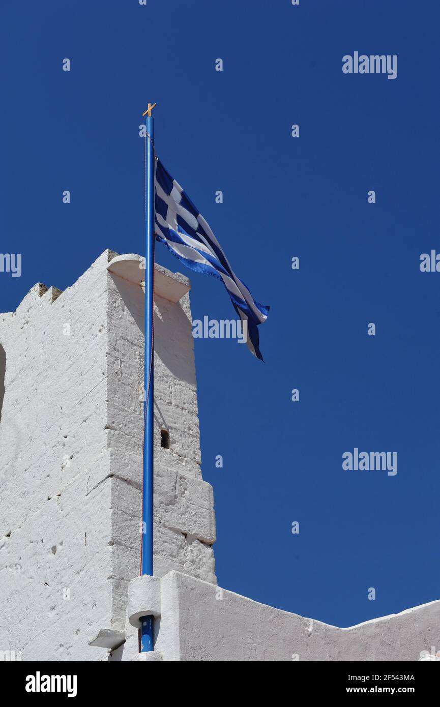 Greek flag swaying from white tower against clear blue sky in Rhodes ...