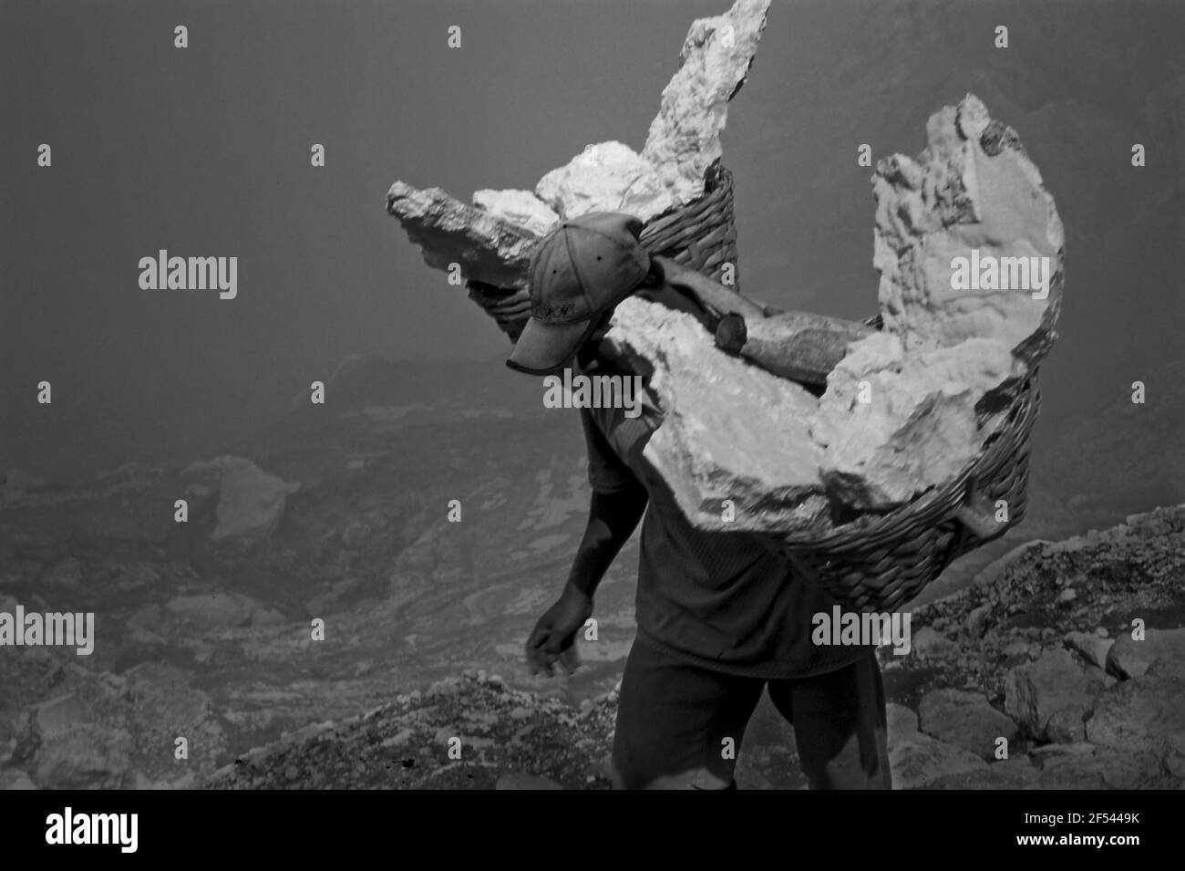 A sulfur miner carrying sulfur chunks from the fumarole, hiking on the ...