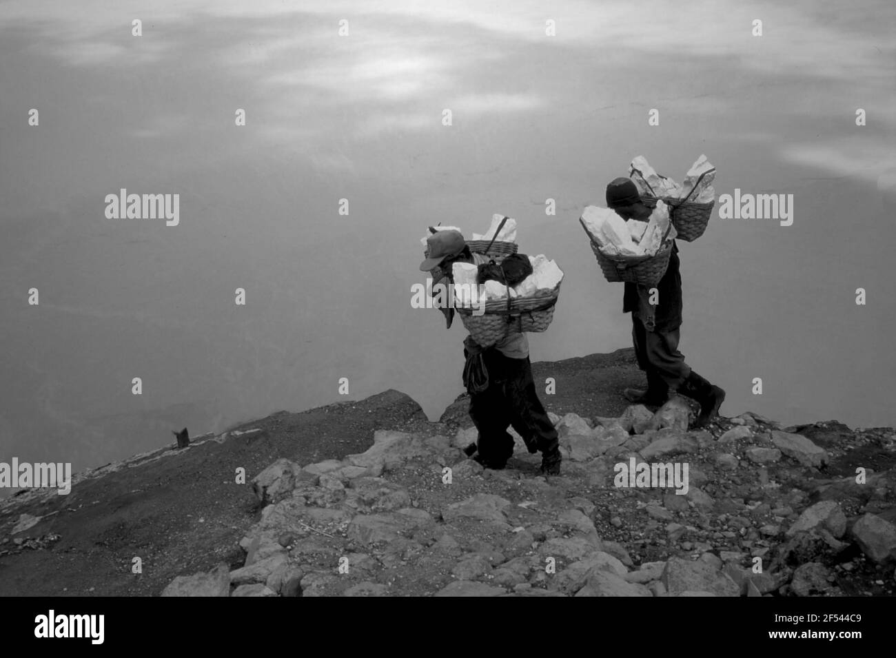 Sulfur miners carrying sulfur chunks from the fumarole, hiking on the ...