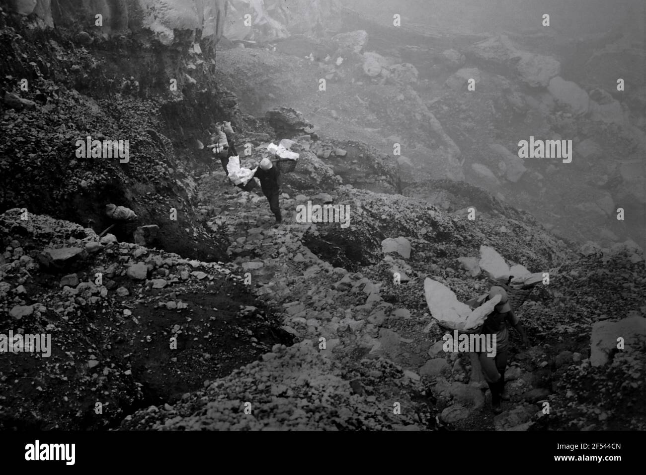Sulfur miners carrying sulfur chunks from the fumarole, hiking on the ...