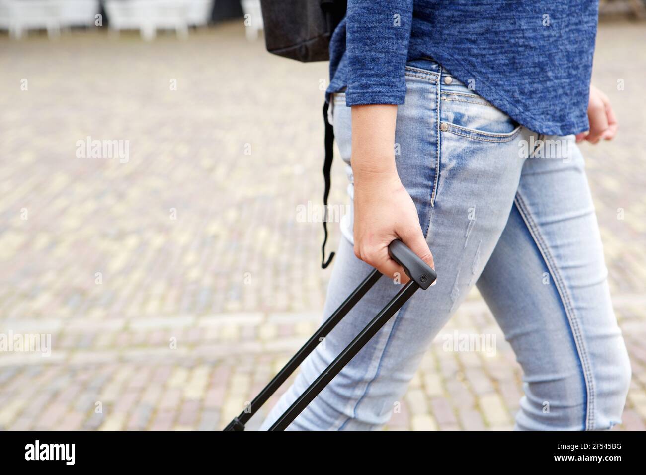 Close up portrait of woman pulling luggage outdoors on city street ...
